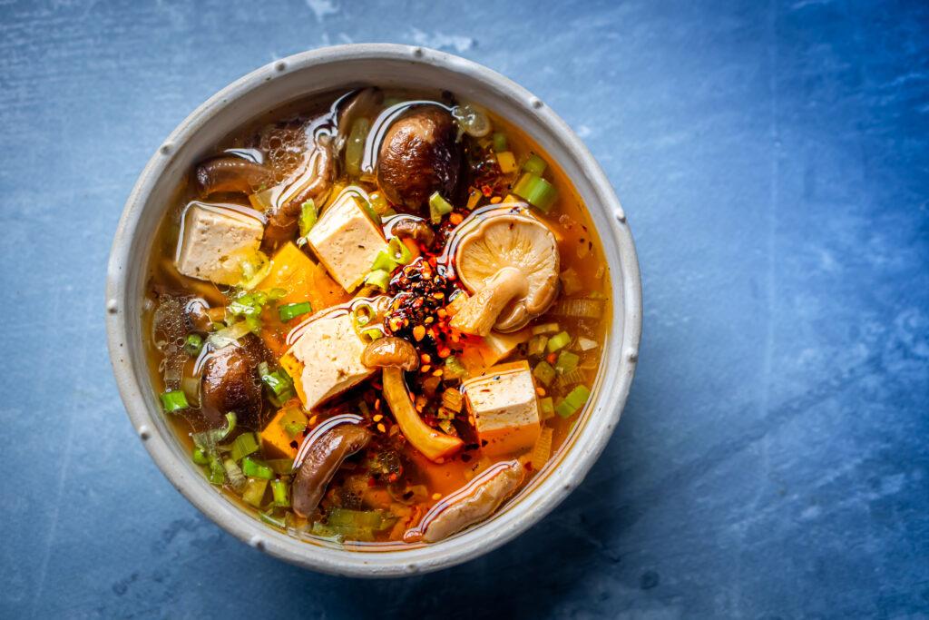 Heldere paddenstoelensoep met tofu, bosui en crispy chili olie